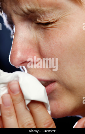 Woman is sneezing sniveling, has a cold or an allergy, uses a soft ...