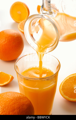 A glass of fresh orange juice and orange fruits on a wooden table ...