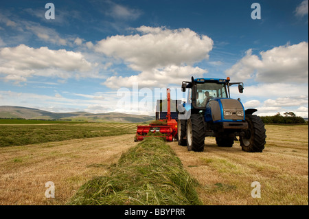 Valtra tractor pulling a Kverneland forage harvester and trailer making ...