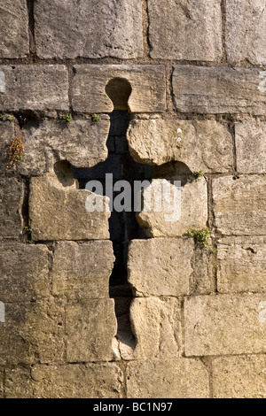 ancient medieval cross shaped arrow slit on the wall of an old castle ...