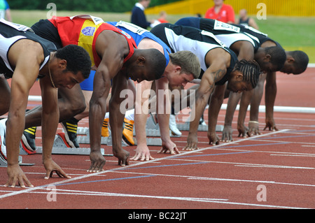 Runners with hands on start line on the track for a race, ready to run ...