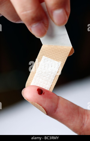 Plaster applyed to a little wound on a finger Stock Photo - Alamy