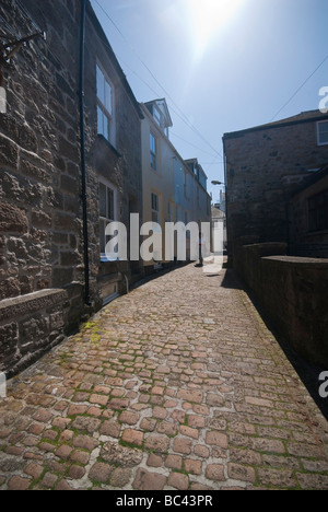 St Ives Cornwall cobbled street with white cottages and granite walls ...