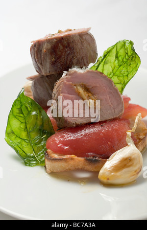 Pork fillet, tomatoes & deep-fried basil on toast Stock Photo - Alamy