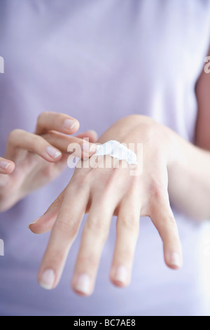 Woman applying cream on hands on bright background Stock Photo - Alamy
