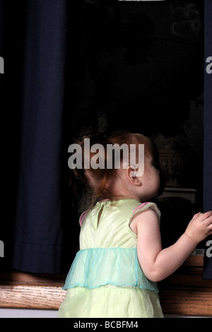 A young girl peeking out her bedroom window at night Stock Photo - Alamy