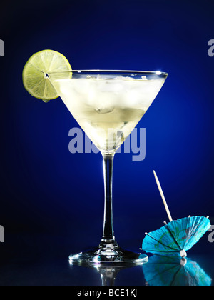 Glass with blue margarita cocktail garnished with lime zest and ...