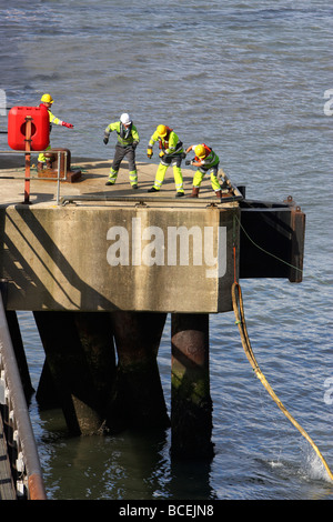 shore crew pull safety line connected to ship rope onto quay while ...