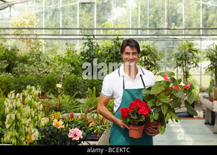 Smiling florist looking at the plant on the porch Stock Photo - Alamy