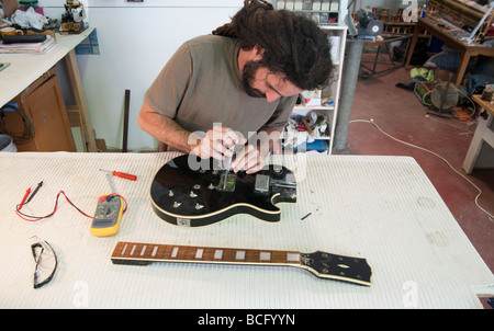 Young man repairing an electric guitar in a workshop Stock Photo - Alamy