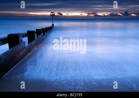 Dawn breaking over wooden groyne at Swanage on the Dorset Purbeck coast ...