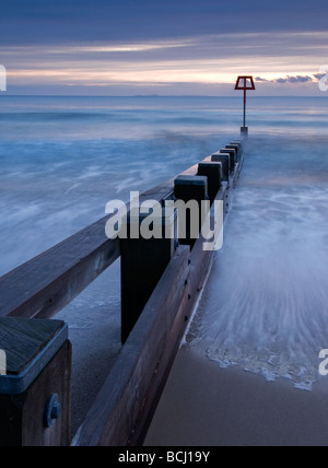 Dawn breaking over wooden groyne at Swanage on the Dorset Purbeck coast ...