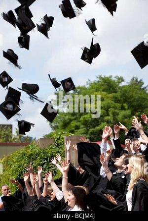 Graduates throw their mortar boards into the air after graduating at ...