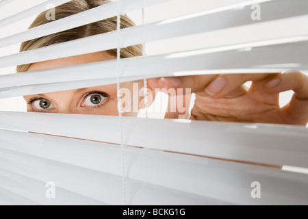 Woman peeking through some window blinds Stock Photo - Alamy
