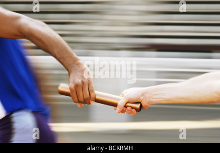 Close-up of hands exchanging a relay baton (also signifying teamwork ...