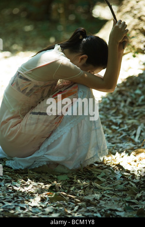 Crouching sad woman holding her hand Stock Photo - Alamy