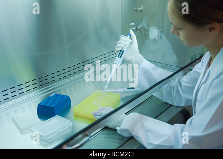 Cropped view of scientist in protective uniform holding vaccine near ...