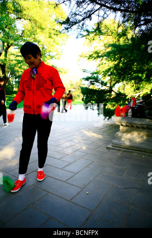 Chinese woman practicing Jianzi, an ancient Chinese game, Beihai Park ...