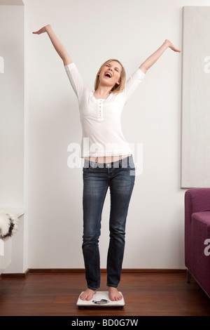 Happy woman standing on scale Stock Photo - Alamy