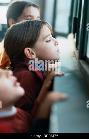 Three kids peeking out a window Stock Photo - Alamy