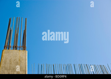 rebars or reinforcing bars from a concrete pillar with blue sky as ...
