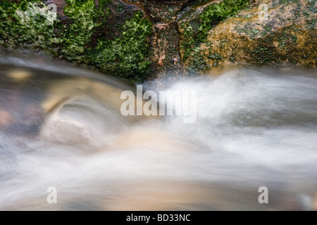 Photograph of fast moving water flowing against a wall over rocks and ...
