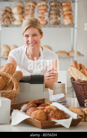 Portrait of friendly female baker with fresh bread smiling in bakery ...