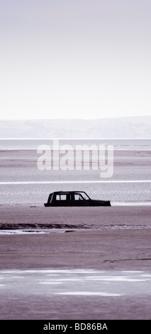 Side view of a partially submerged car on the treacherous beach of ...