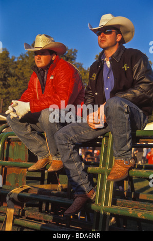 Two cowboys sit on fence overlooking rodeo arena Stock Photo - Alamy