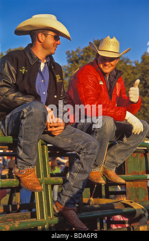Two cowboys sit on fence overlooking rodeo arena Stock Photo - Alamy