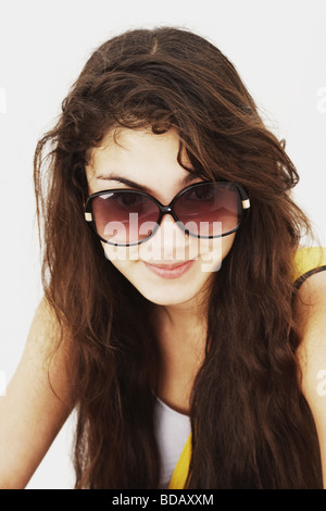A smiling woman wearing white sunglasses and a white shirt stands in ...