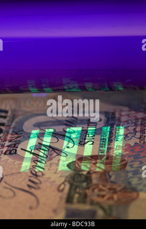using an ultra violet black light to check a twenty pound note bank of ...