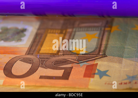 using an ultra violet black light to check a twenty pound note bank of ...