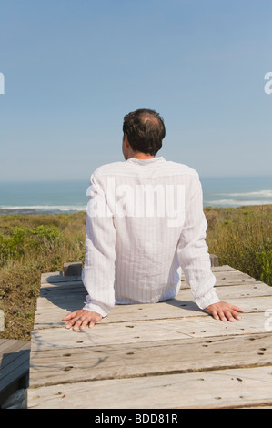 Rear view of man sitting in snow and holding blank screen smart phone ...