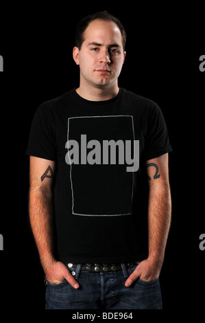 Serious man in jeans and white t-shirt is standing and looking away ...