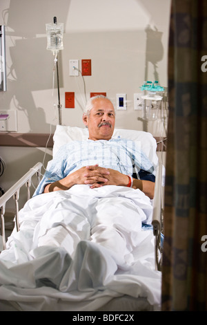 Elderly man laying in hospital room bed wearing cerival collar, with iv ...