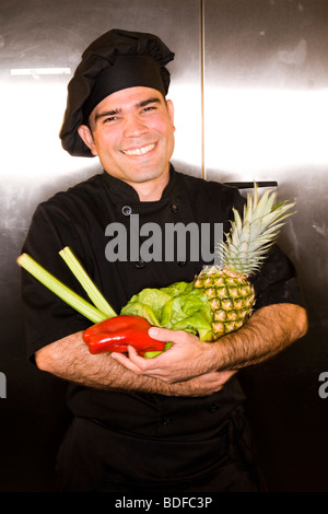 Portrait of a cheerful male chef cook in uniform holding blank board ...