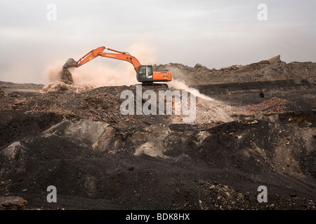 Diggers loading trucks with dusty ore and rock to expose coal in the ...