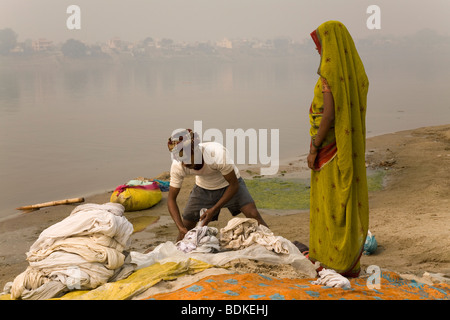 People washing clothes in the Ganga Ganges river by the sewage pipe ...
