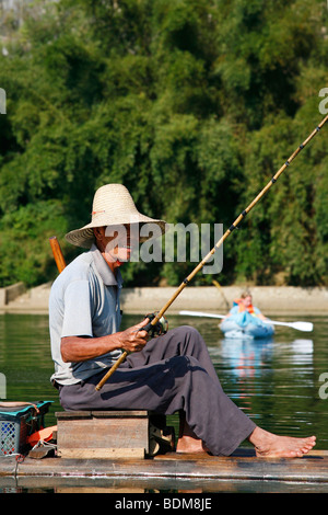 Guangxi, China: Fisherman on bamboo raft tossing net on Li River near ...