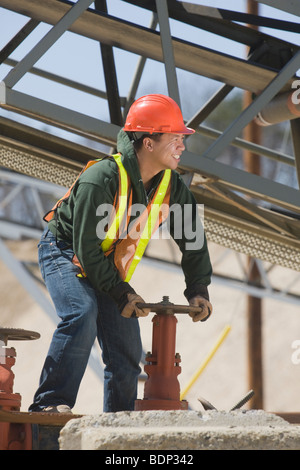 Asian worker at construction machinery of construction site or mining ...