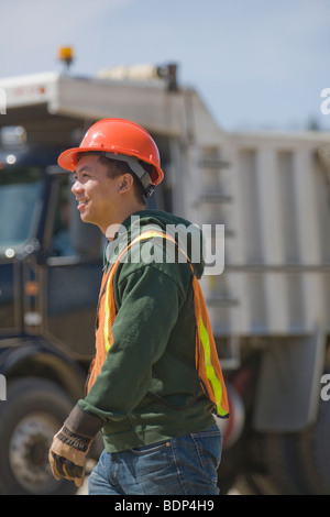 Site engineer with a safety equipment walking and carrying blueprints ...