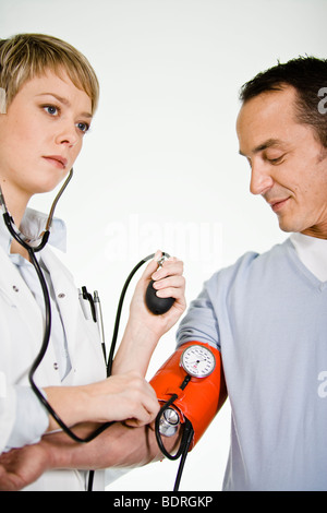 Female doctor using blood pressure monitor measurement device at clinic ...