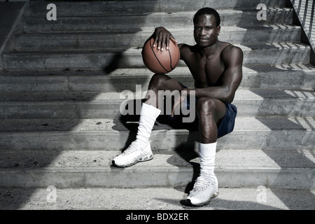 Dark-skinned basketball player sitting on stairs, portrait Stock Photo ...