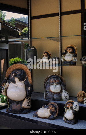 Japanese tanuki (raccoon dog) figurines in a row on a concrete wall ...