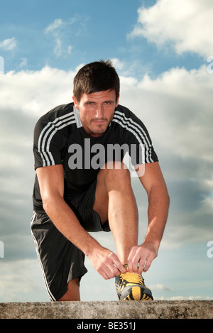 Football player tying his shoe lace in dressing room Stock Photo - Alamy