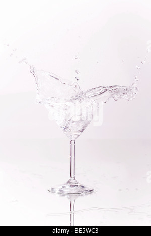 Dropping ice cubes into martini glasses on white background Stock Photo - Alamy