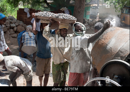 Indian construction workers mixing rock sand and cement to make ...
