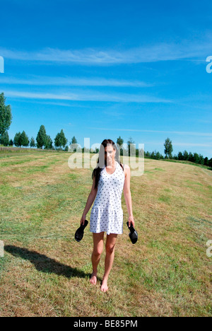 Women walk holding their shoes during a severe thunderstorm at the end ...