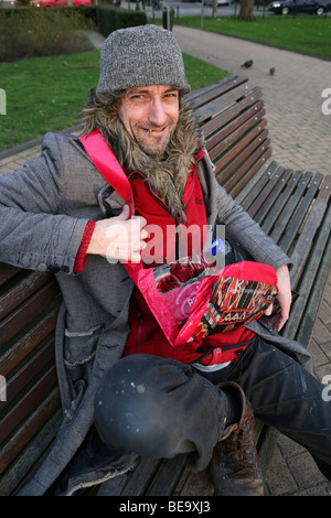 Crazy and happy homeless wanderer sitting on bench outside Stock Photo ...